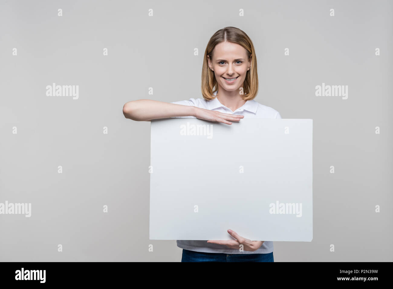 happy attractive woman presenting empty blank board, isolated on grey ...