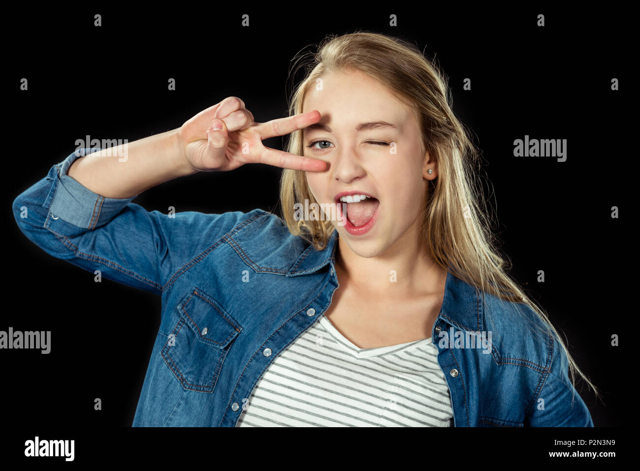 playful teen girl winking at camera isolated on black Stock Photo - Alamy