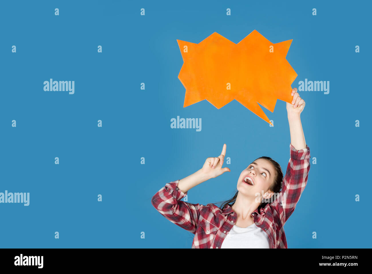 teen girl pointing at blank speech bubble isolated on blue Stock Photo ...