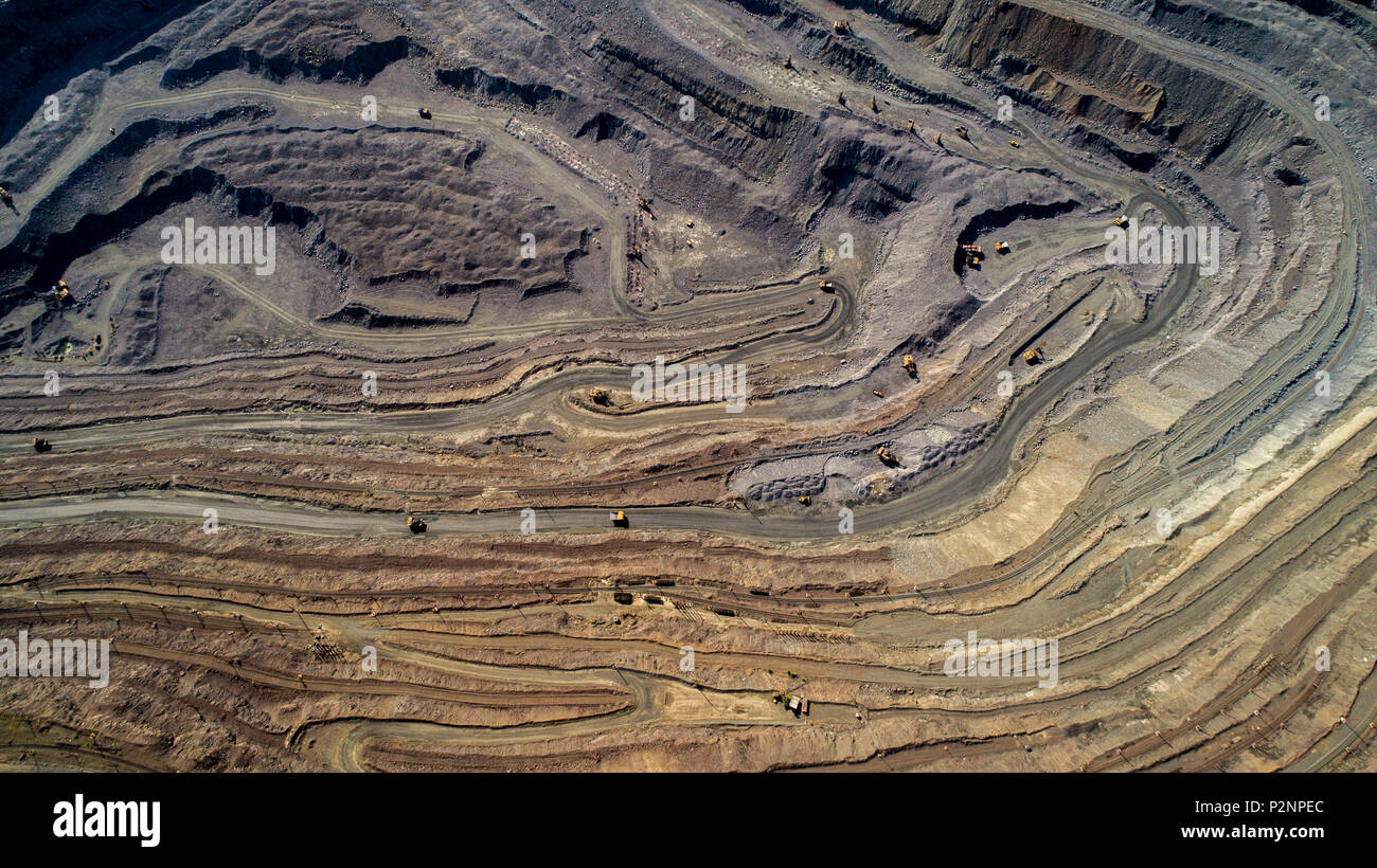 Aerial view of opencast mining quarry with lots of machinery at work ...