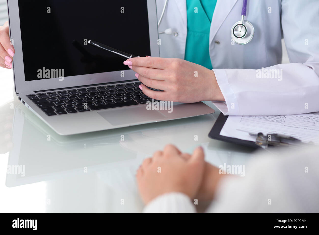 Doctor and patient, close-up. Physician pointing into laptop computer ...