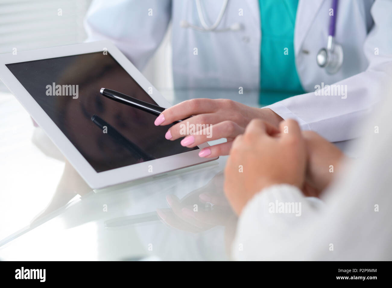 Doctor and patient, close-up. Physician pointing into laptop computer ...
