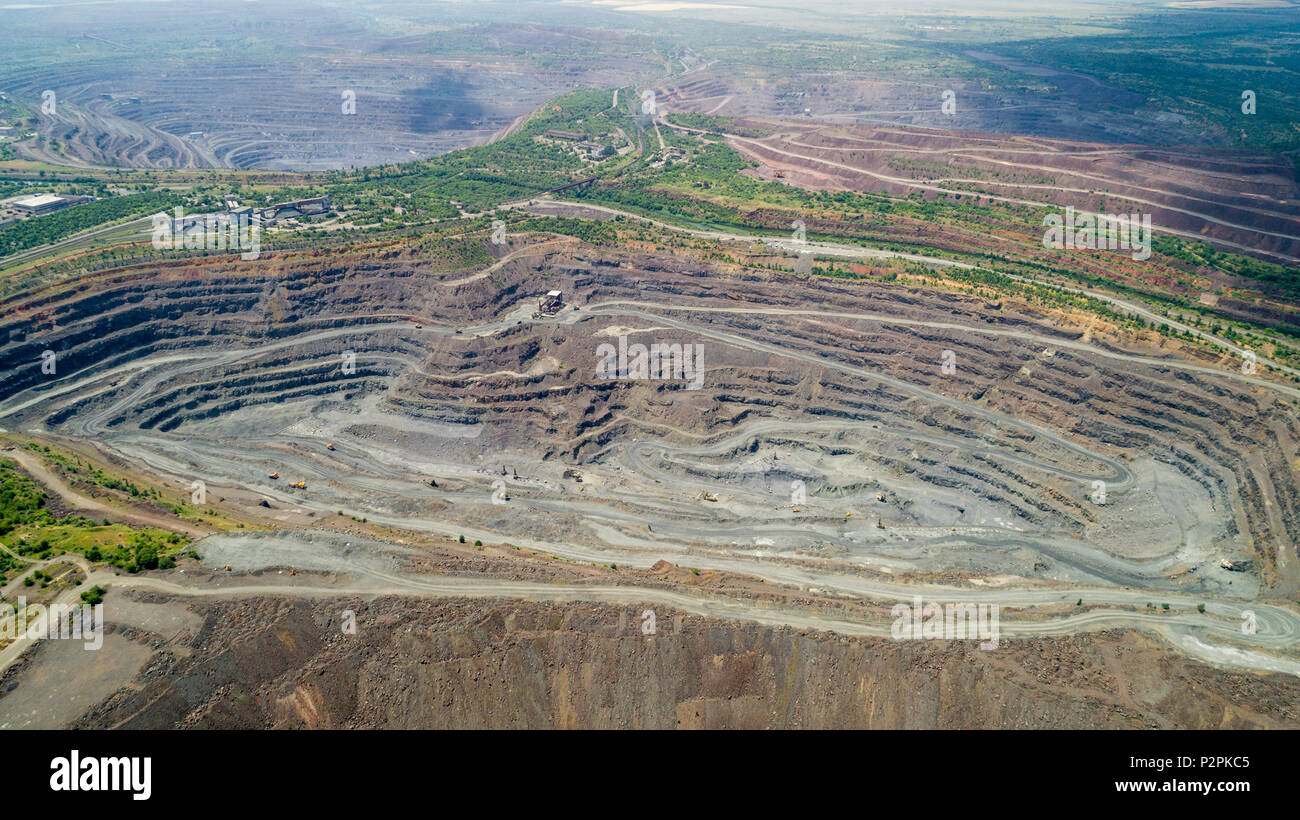 Aerial view of opencast mining quarry with lots of machinery at work ...