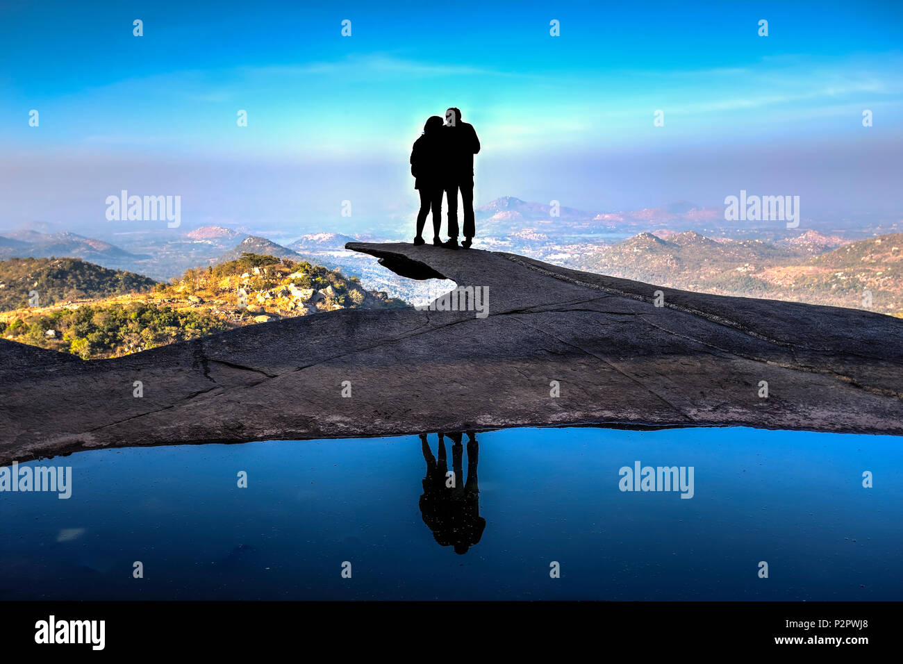 Couple silhouette standing on the edge of a cliff with theirs ...