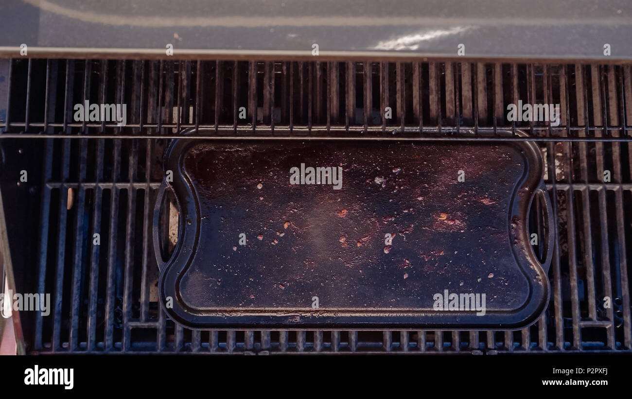 Empty cast iron griddle on outdoor gas grill Stock Photo - Alamy
