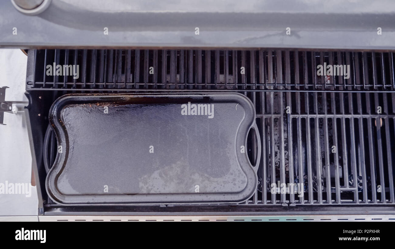 Empty cast iron griddle on outdoor gas grill Stock Photo - Alamy
