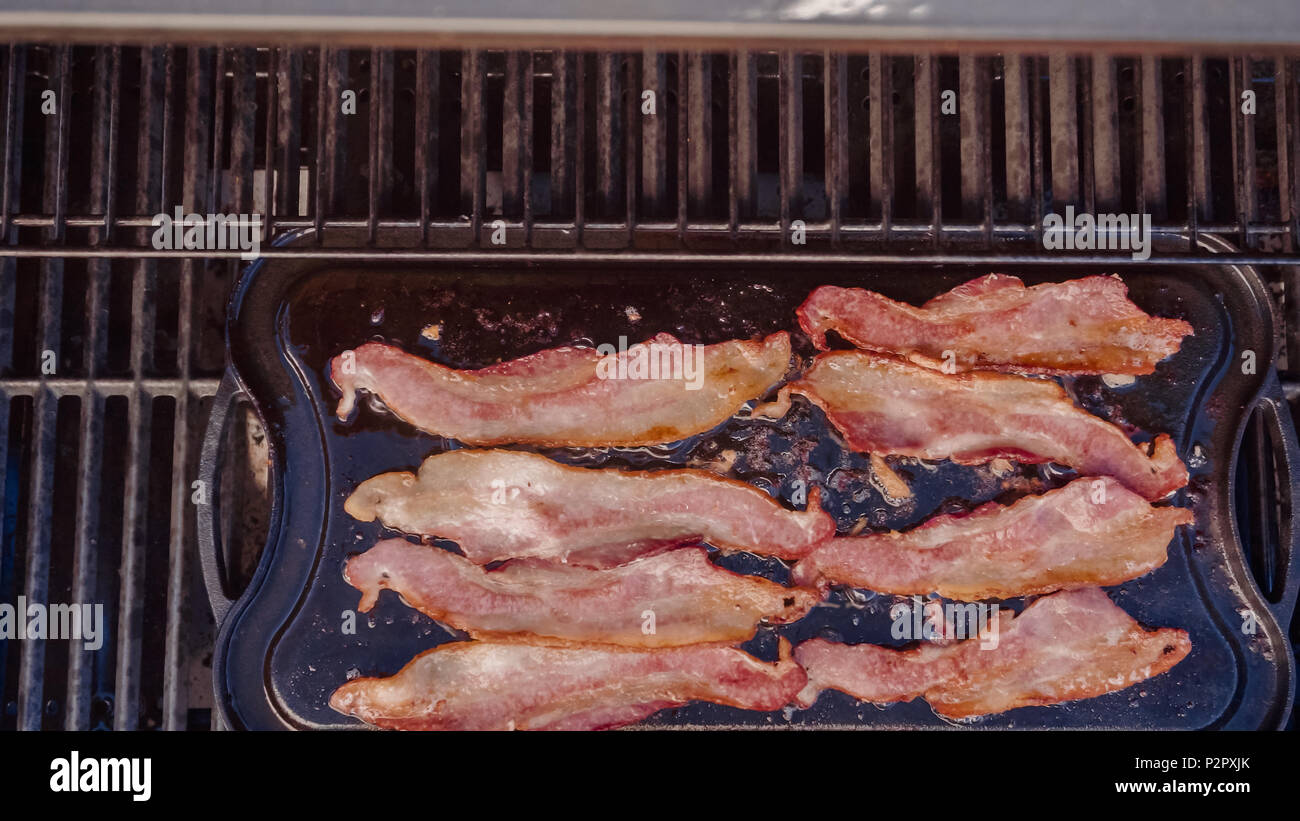 Frying bacon on cast iron griddle in outdoor gas grill Stock Photo - Alamy