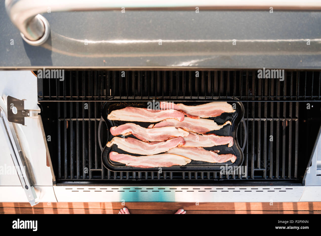 Frying bacon on cast iron griddle in outdoor gas grill Stock Photo - Alamy