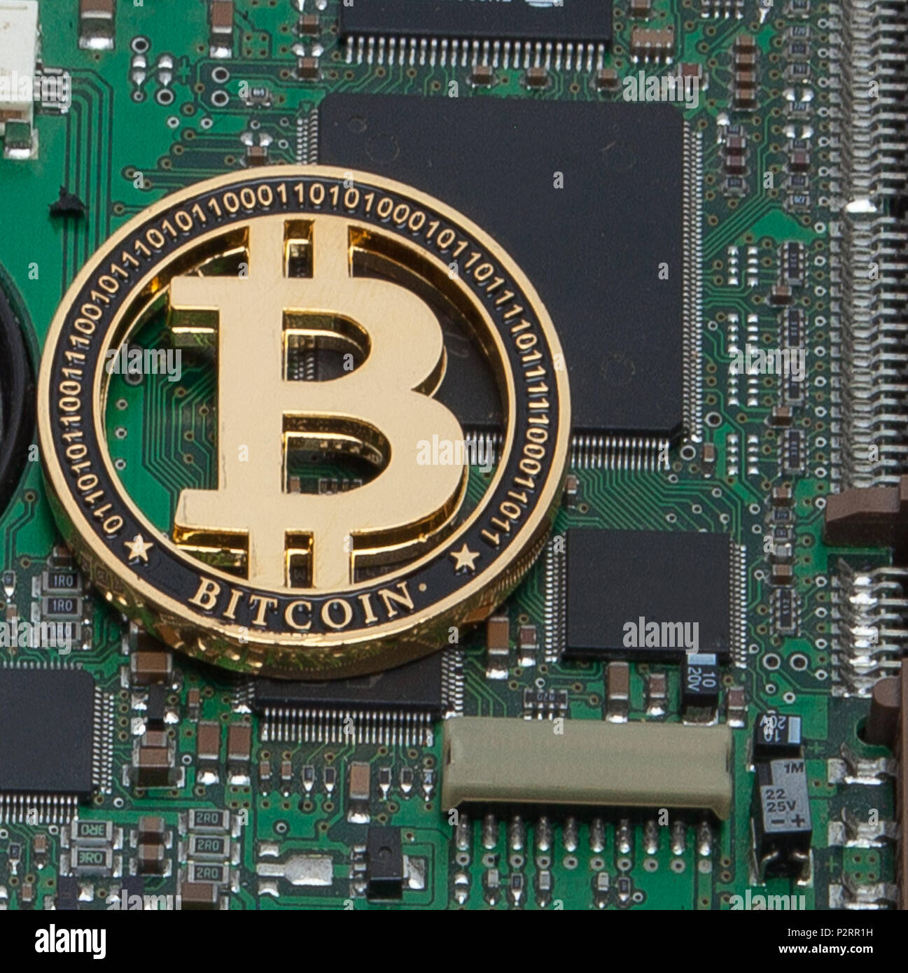 Close-up of gold bit coin, computer circuit board with bitcoin processor and microchips ...