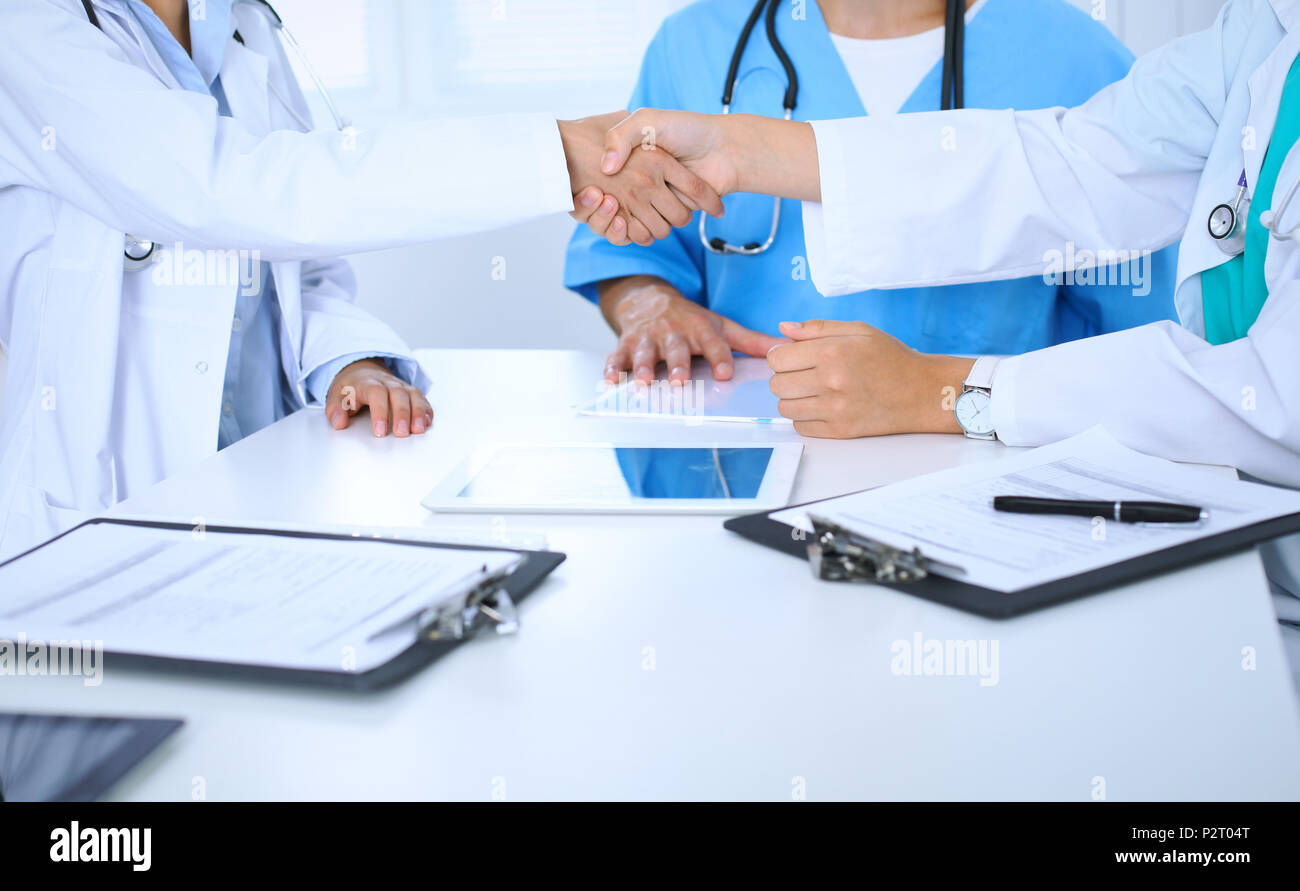 Two doctors shaking hands to each other at meeting. Teamwork and ...