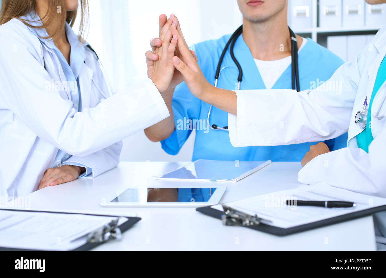 Group of doctors joining hands at meeting. Teamwork and success in ...