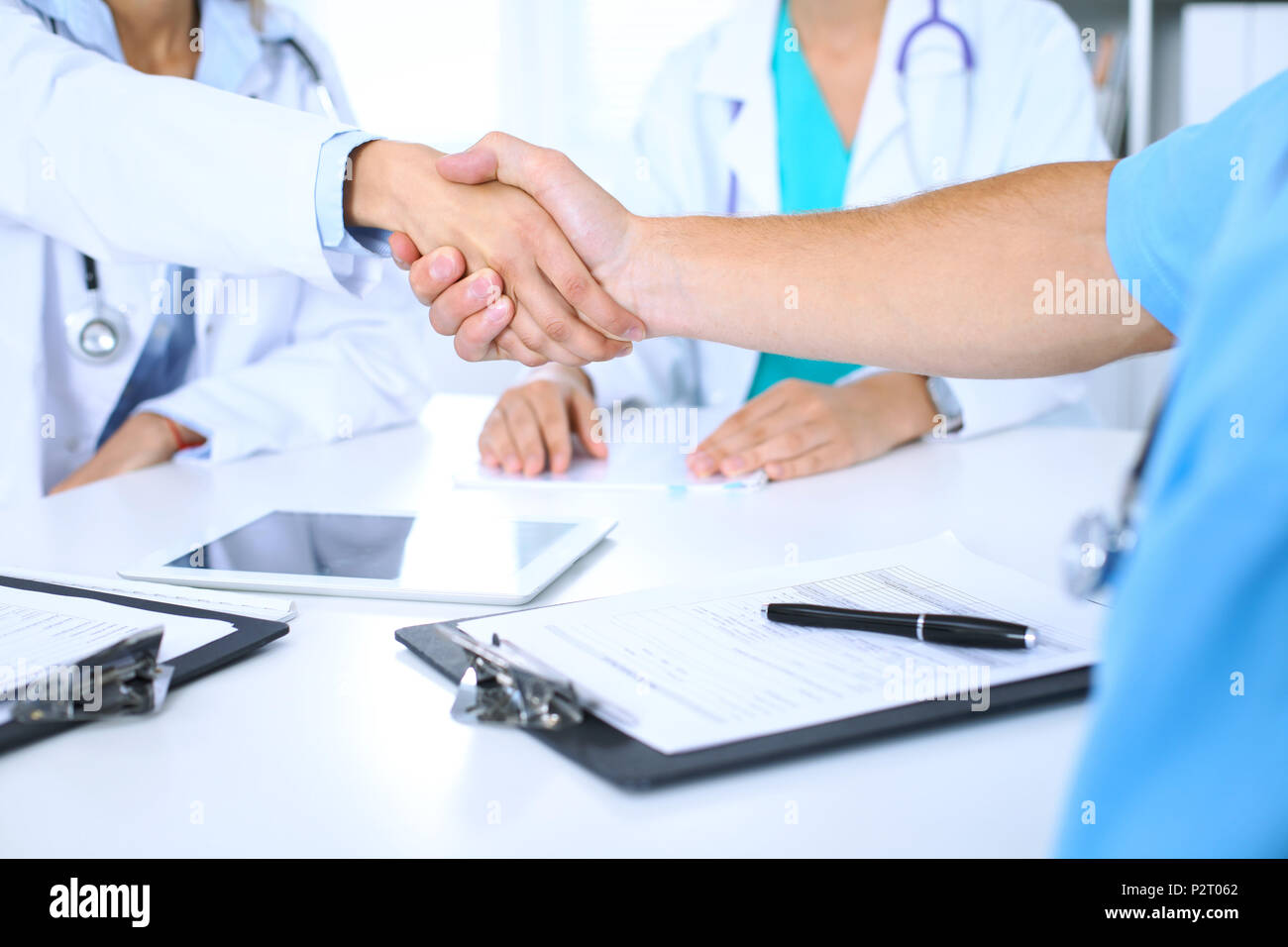 Two doctors shaking hands to each other at meeting. Teamwork and ...