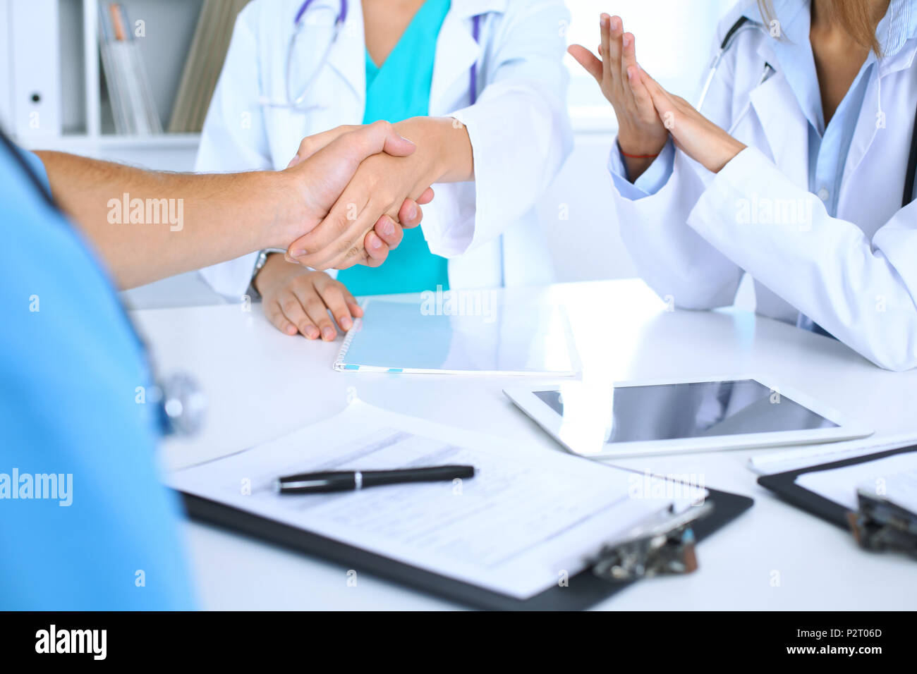 Two doctors shaking hands to each other at meeting. Teamwork and ...