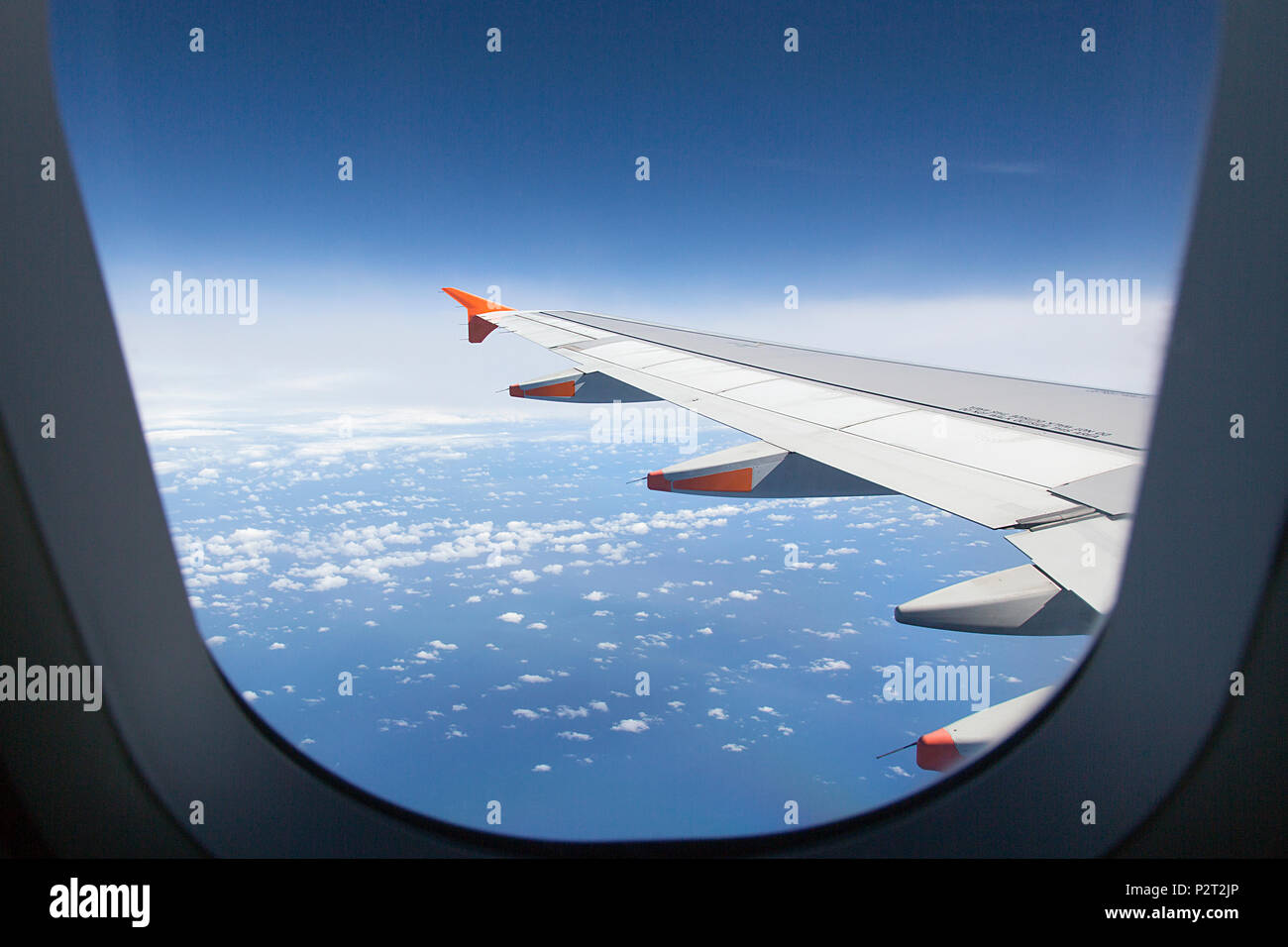 Looking through aircraft window during flight. Aircraft wing over blue ...