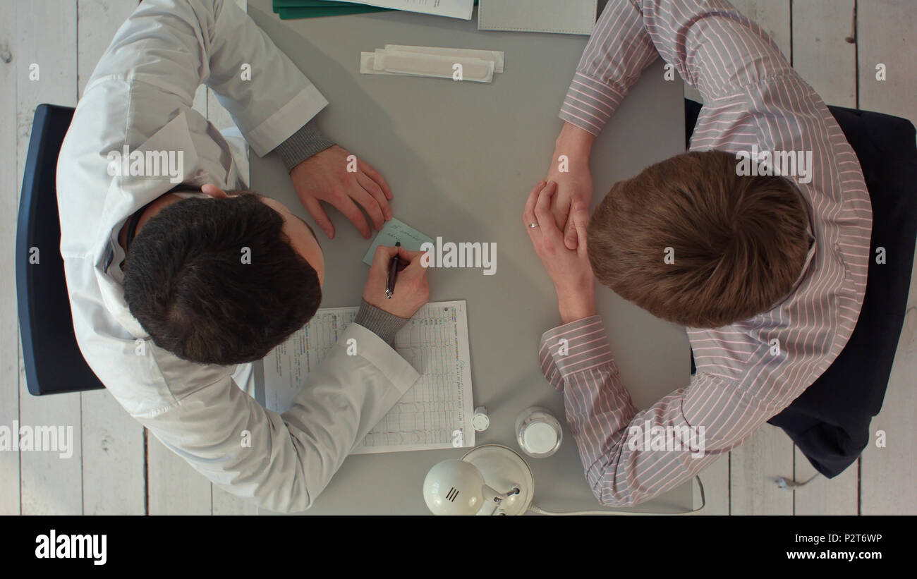 Top view of Doctor writing on a medical chart with patient Stock Photo ...