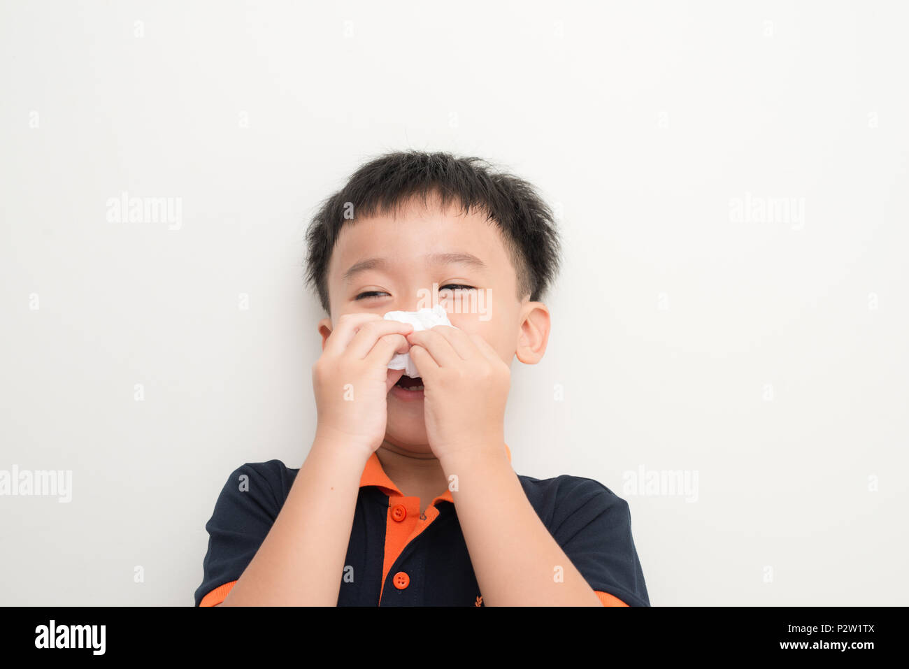 Cute little boy sneezing in tissue on white background Stock Photo - Alamy