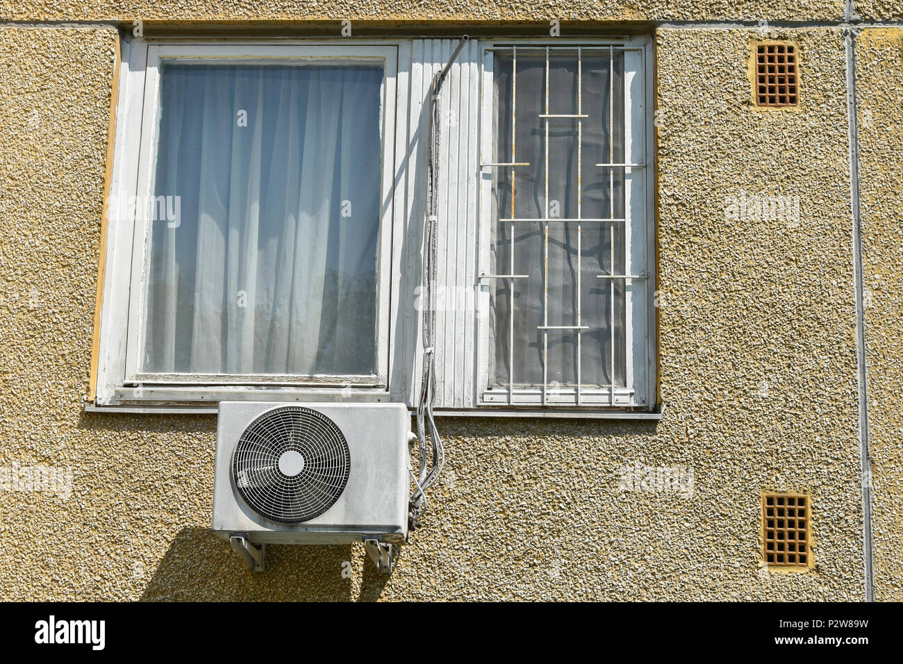 Air conditioner under a window of an apartment building Stock Photo - Alamy
