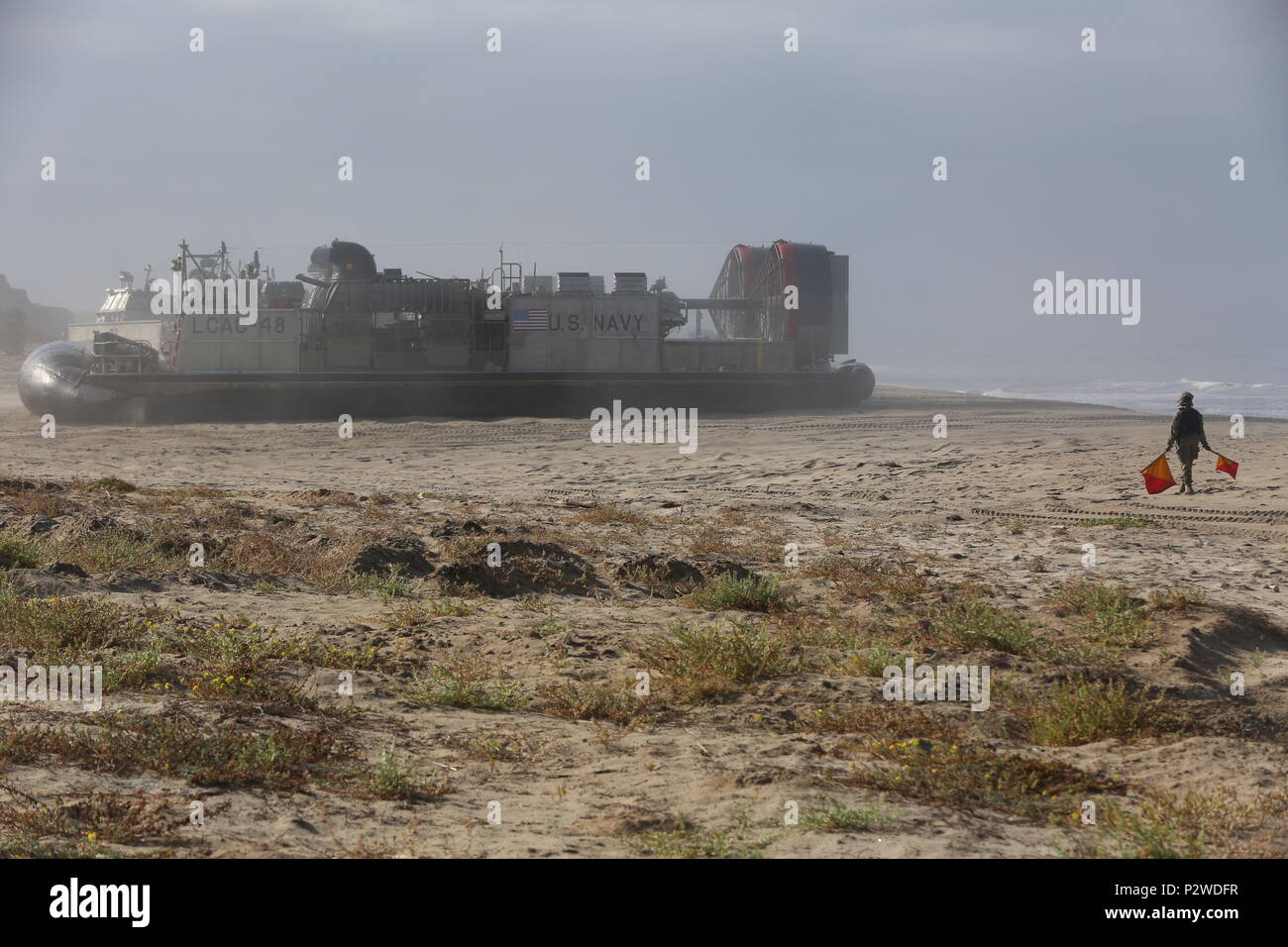 A U.S. Navy Sailor signals a Landing Craft Air Cushion with Assault ...