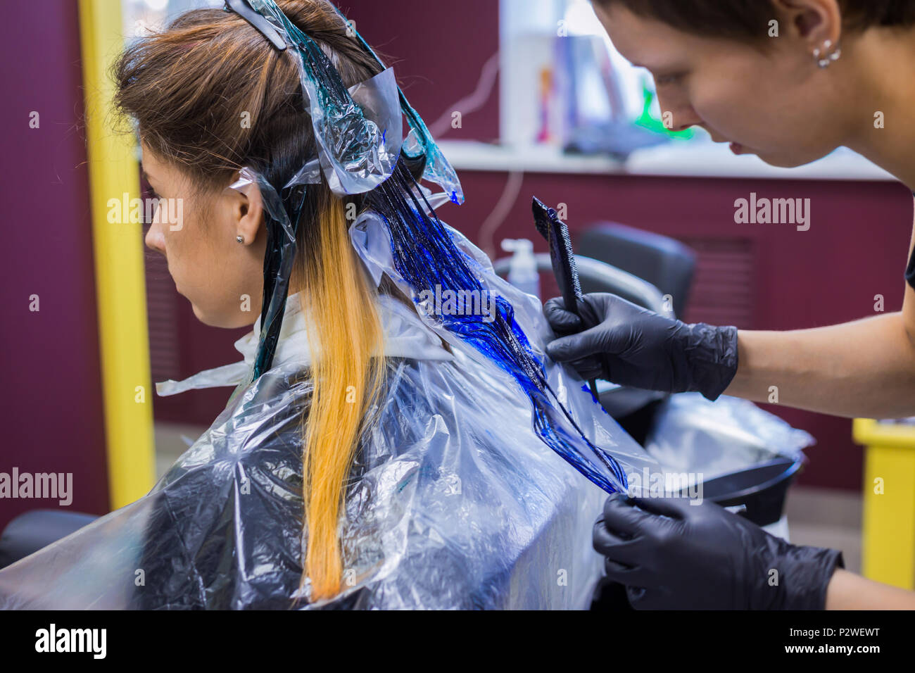 Professional hairdresser, stylist coloring hair of woman client at ...