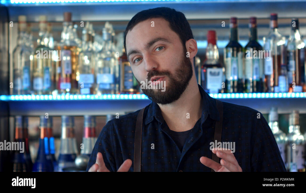 Positive bartender talking to a camera at a bar counter Stock Photo - Alamy