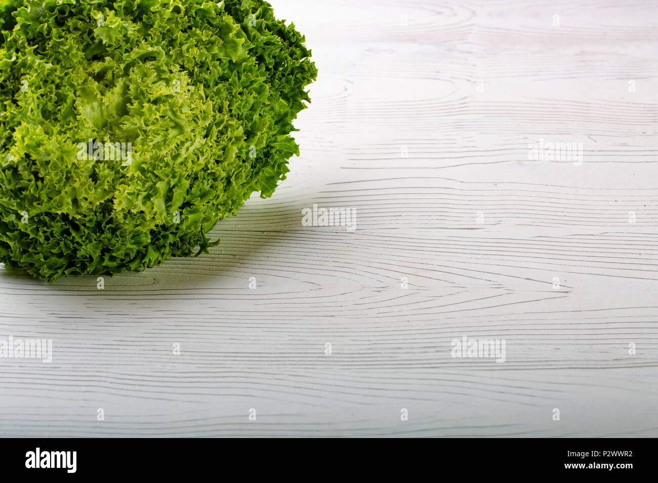Green batavia lettuce salad on white wooden background. Copy space ...