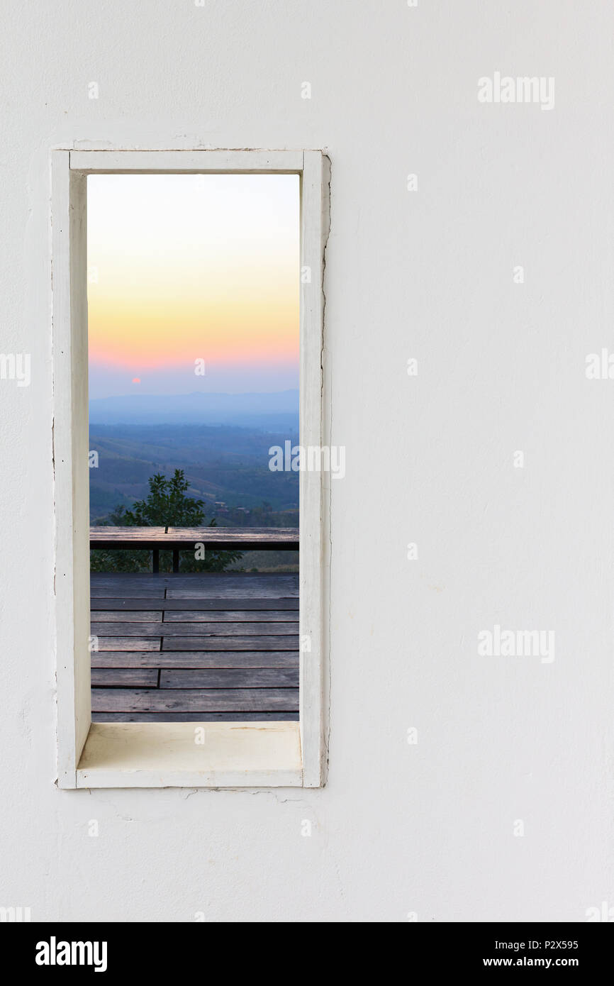 White wall window with sunset mountain view, vertical landscape concept ...