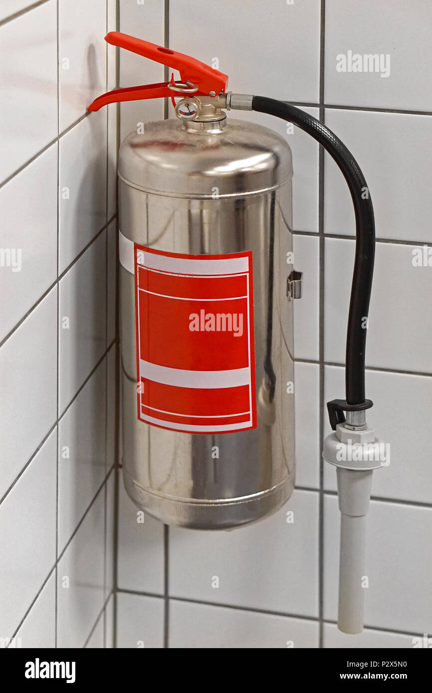 Silver fire extinguisher in building corner Stock Photo - Alamy