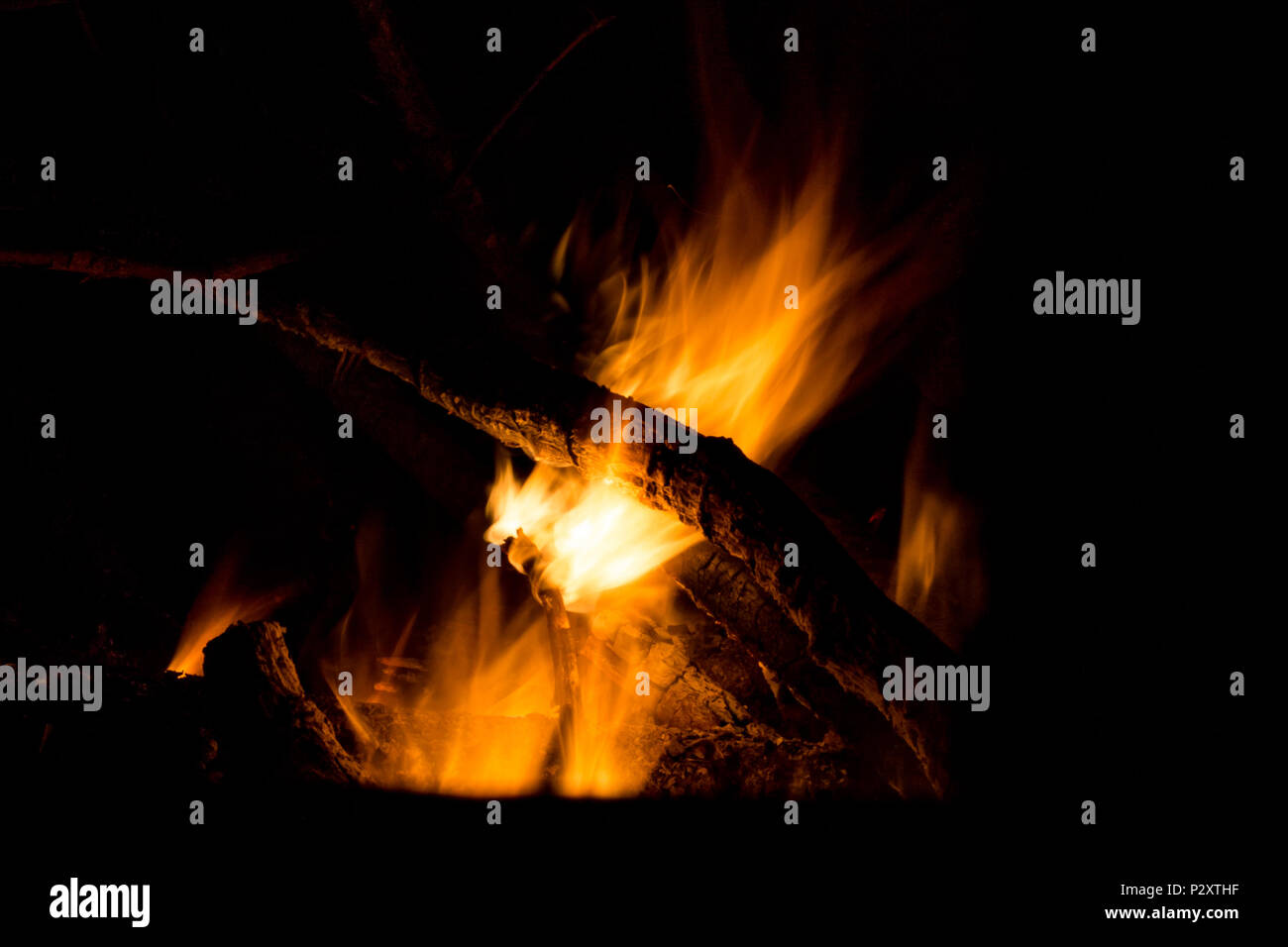 Campfire burning logs and branches in fire at night long exposure close ...