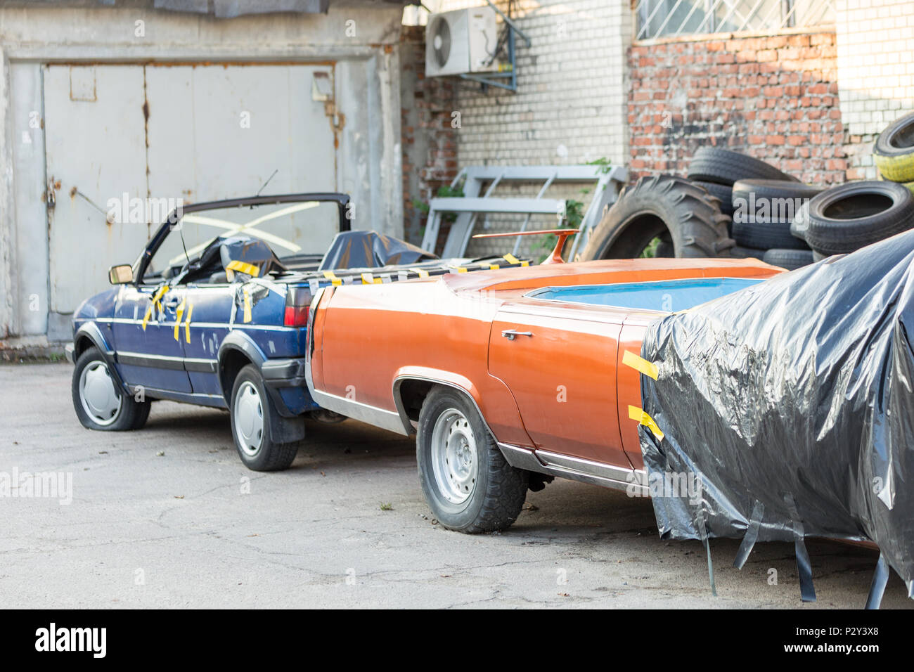 Old wrecked covered car at back yard of workshop. Abandoned convertible ...