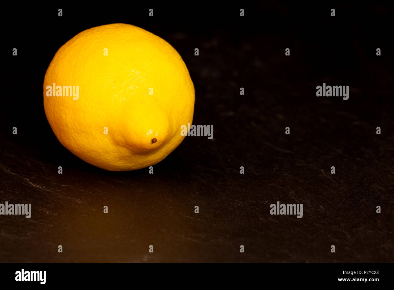 Yellow lemon isolated on a dark background on a slate surface. Fruit ...