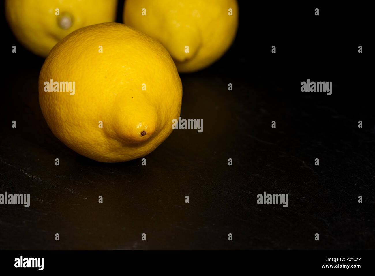 Yellow lemons isolated on a dark background on a slate surface. Fruit ...