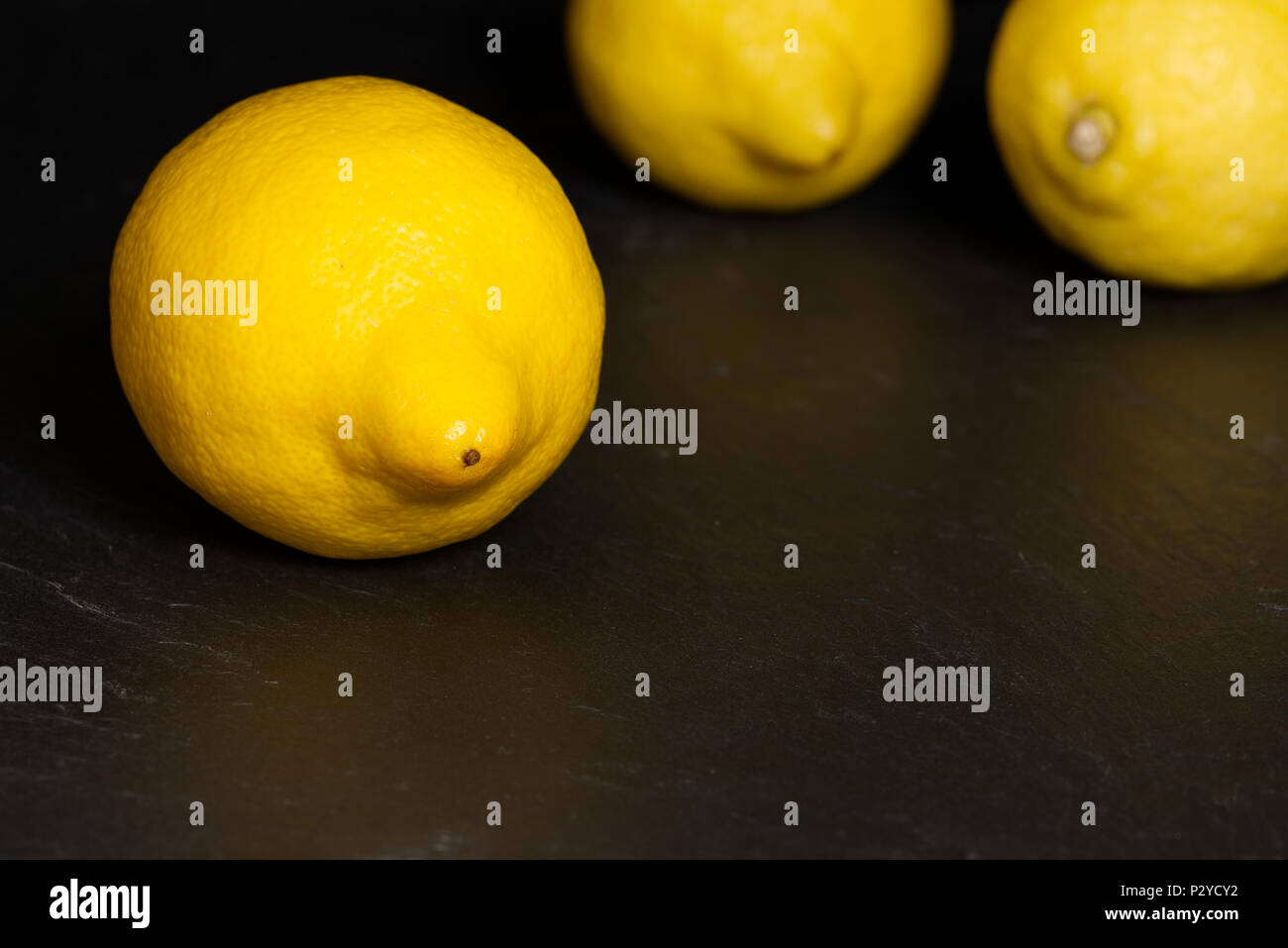 Yellow lemons isolated on a dark background on a slate surface. Fruit ...