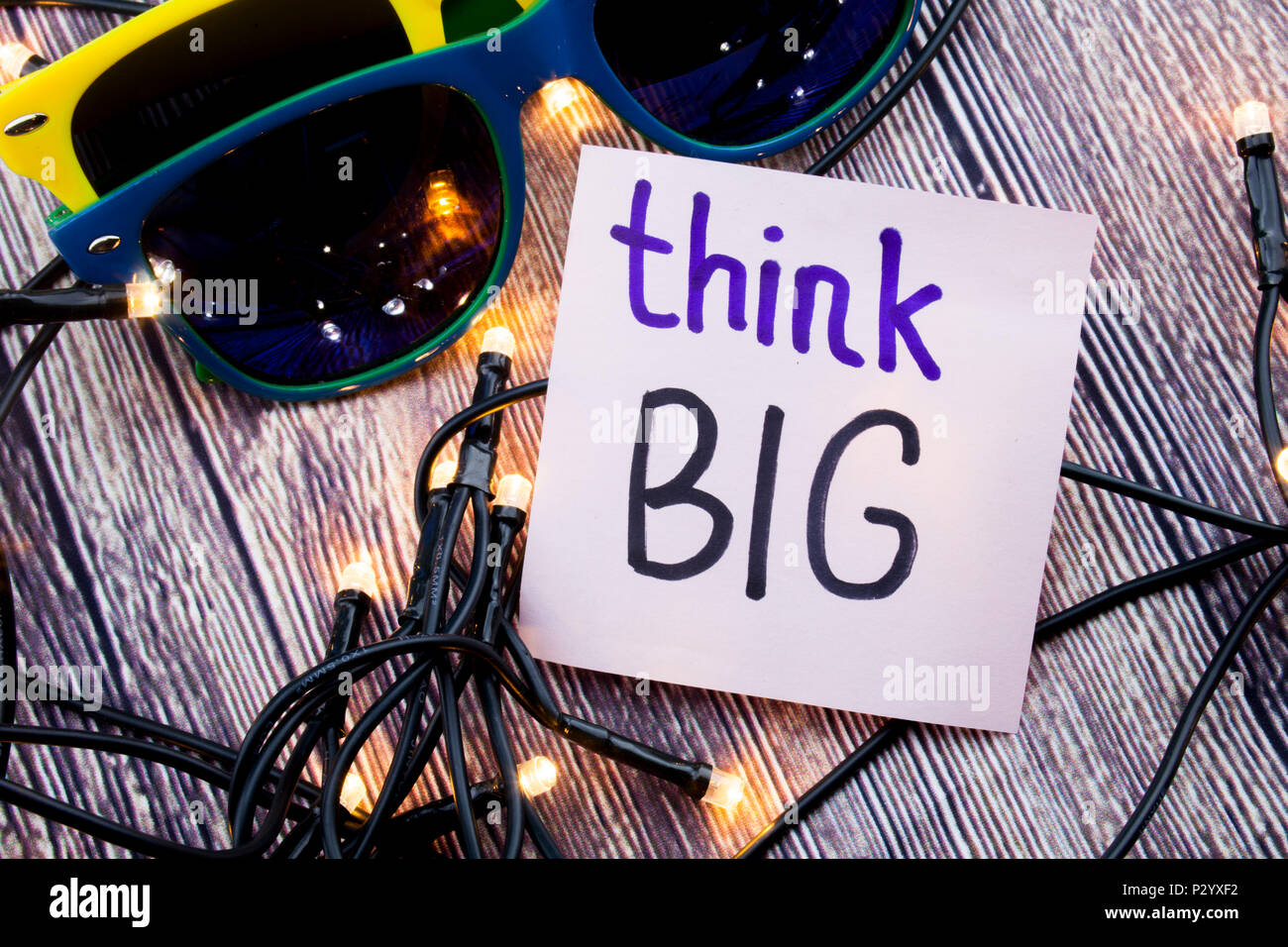 Think big handwritten words on white paper with wooden bark as ...