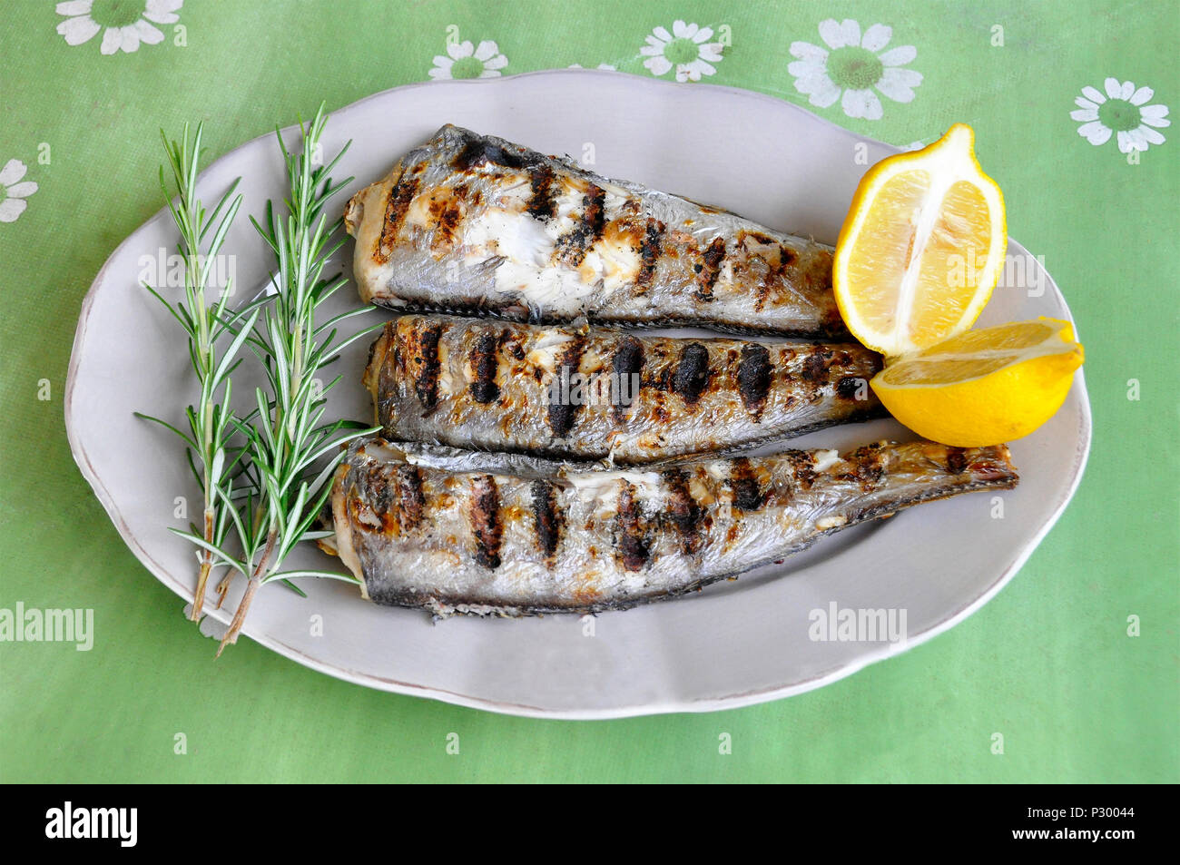 fried grilled fish in white tartle with lemon Stock Photo - Alamy