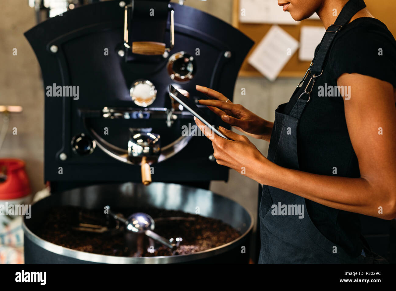 Female barista using digital tablet, standing near coffee roasting ...