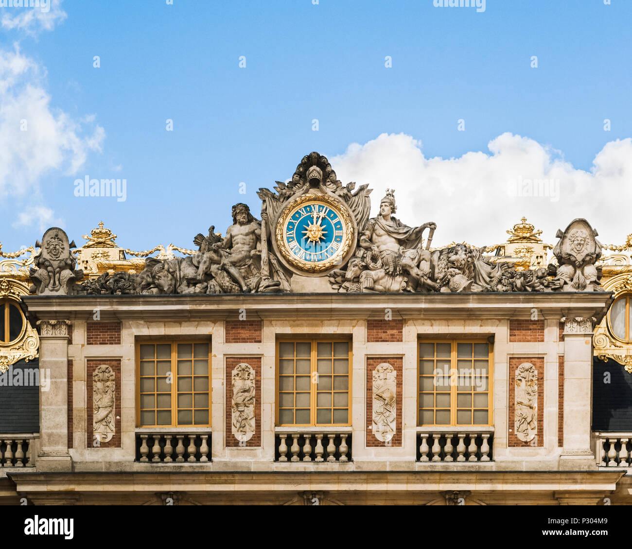 Gold, ornate, clock sitting atop the Chateau de Versailles, against a ...