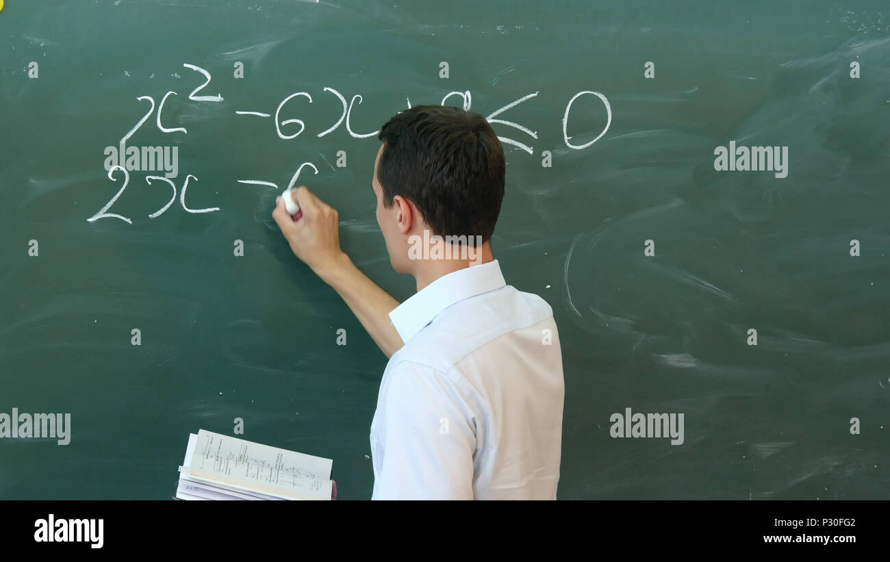 Young teacher writing on a blackboard math formula Stock Photo - Alamy