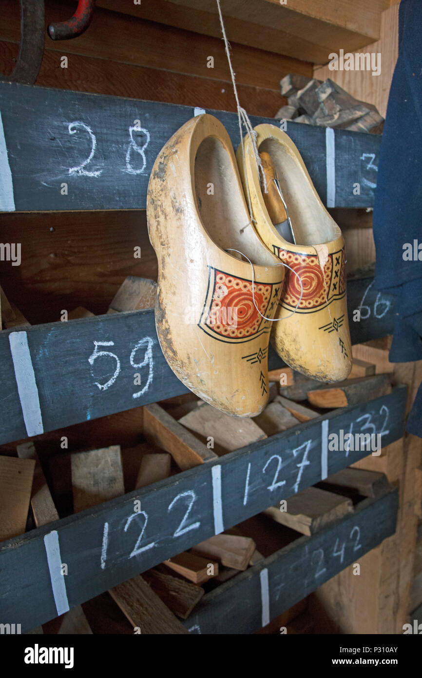 A pair of decorated wooden clogs hanging by shelves inside a 17th ...
