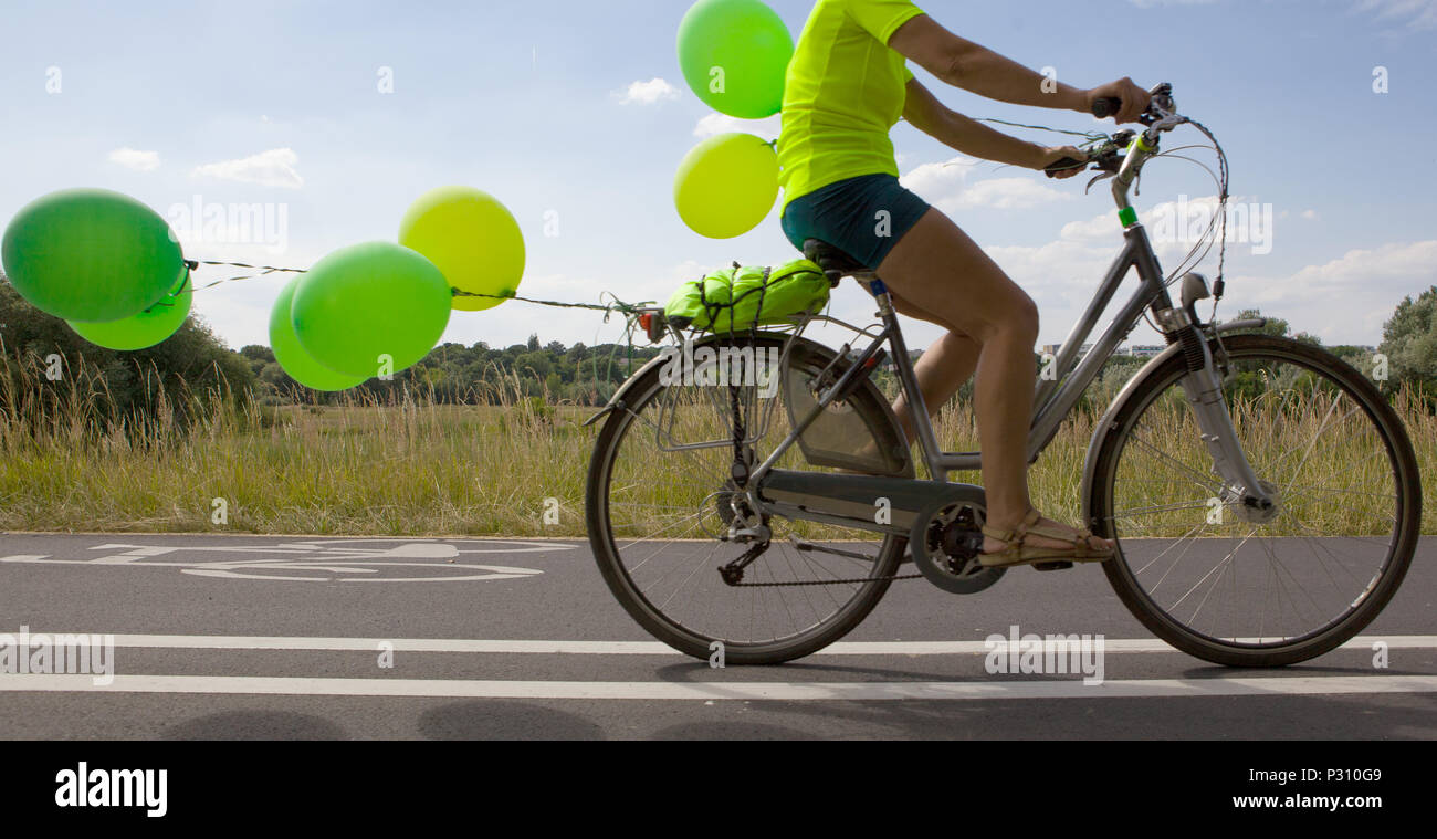 Woman on a Bike with balloons. Green balloons attached to the bicycle ...