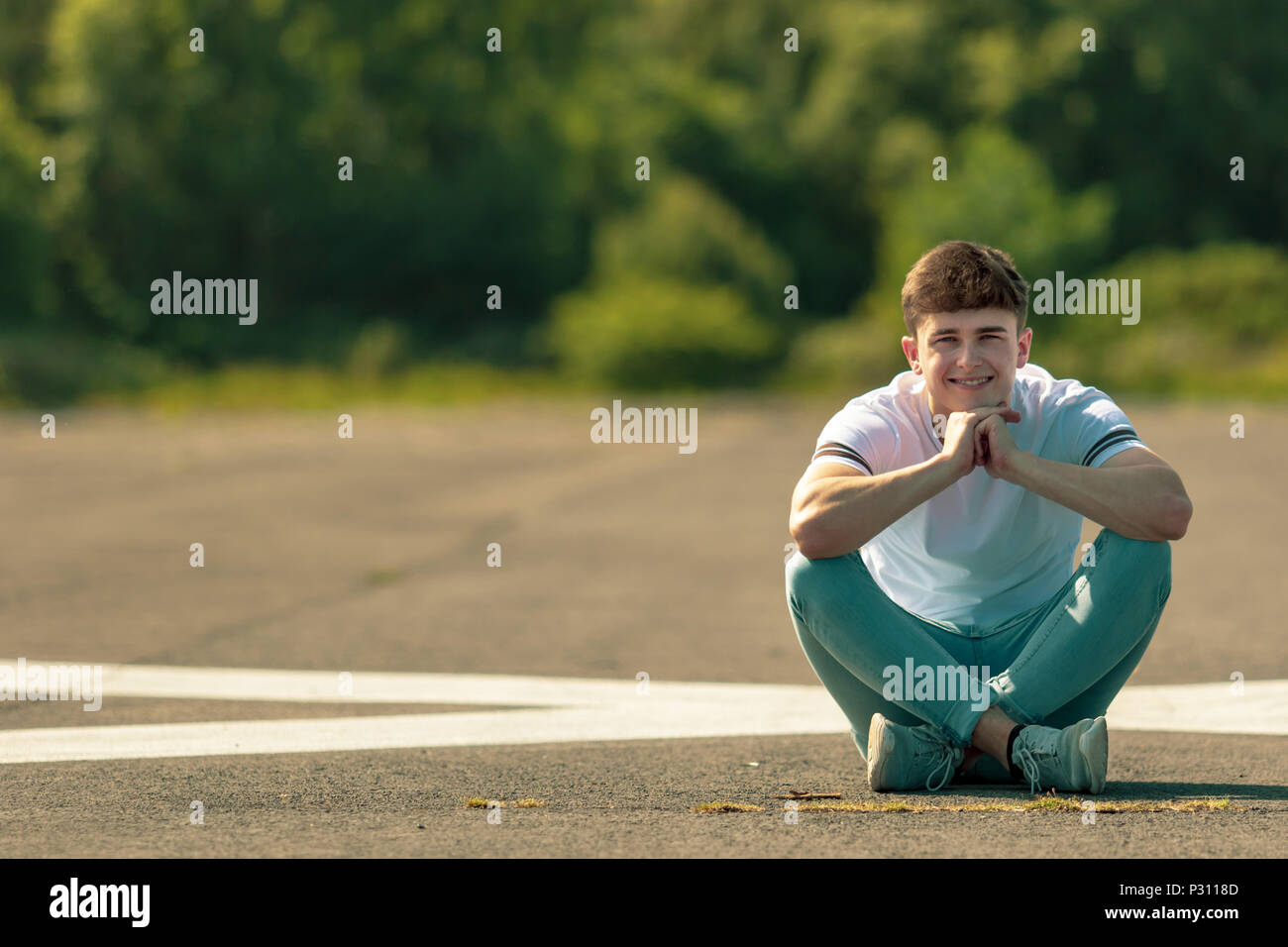 Young adult male sitting outside in the sun Stock Photo - Alamy