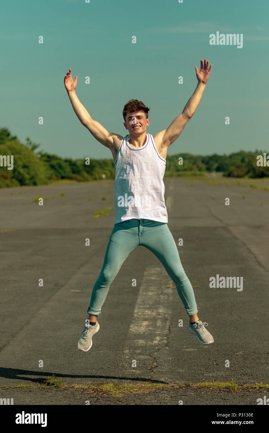 Young adult male jumping outside in the sunshine Stock Photo - Alamy