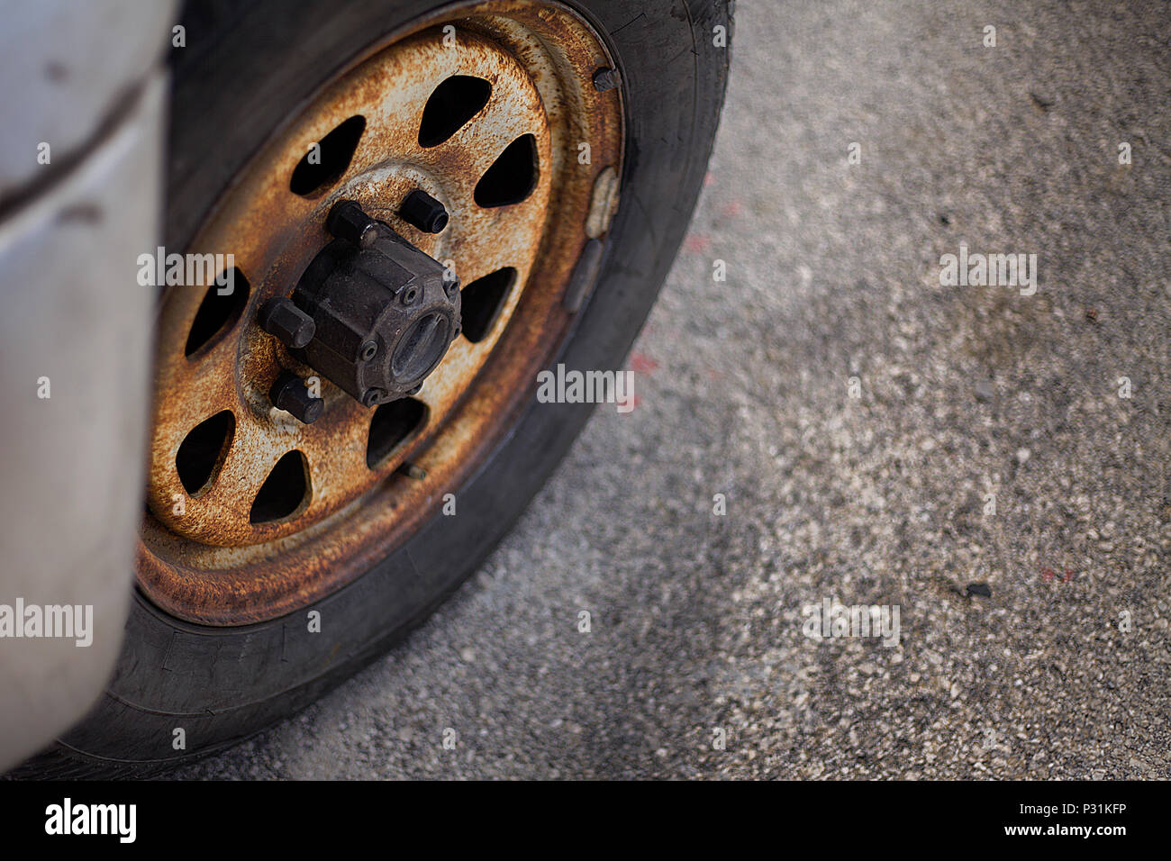 Rusty old truck wheel parked random area. Oxidized black colored ream ...