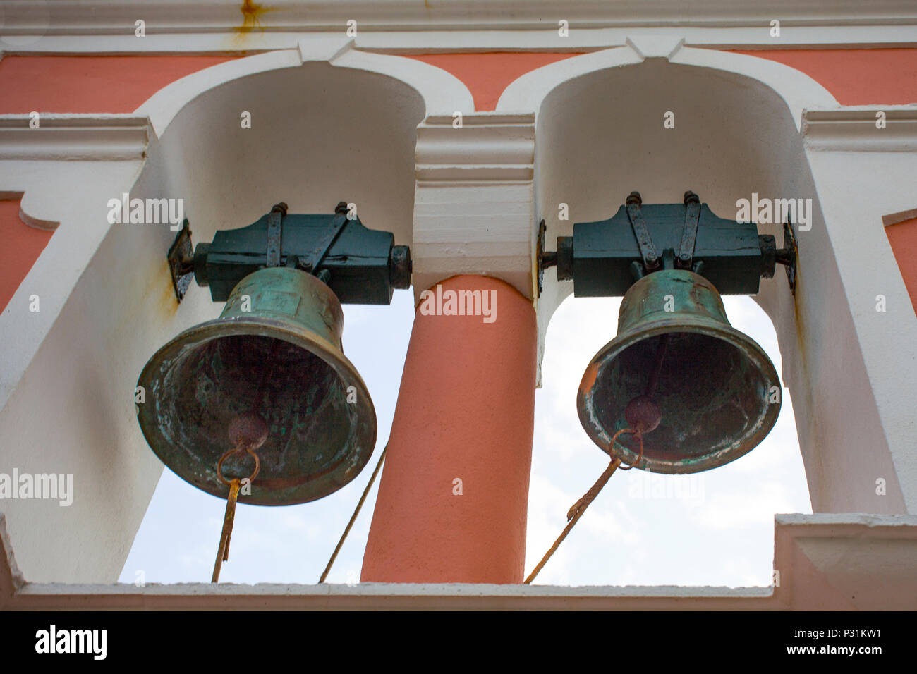 Two large rustic church bells above structure. Building is rusty but ...