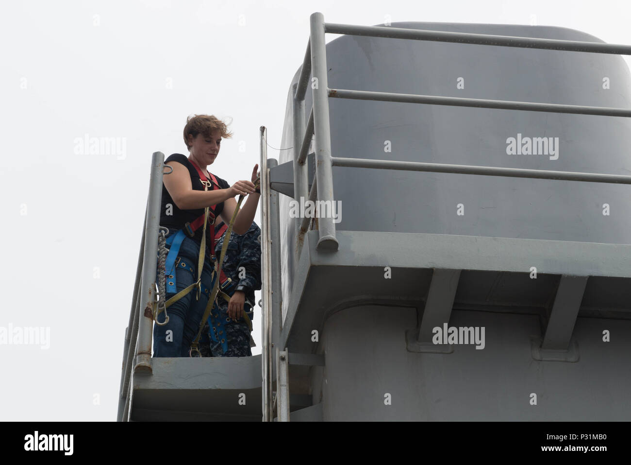 Electronics Technician 3rd Class installs a safety harness after ...