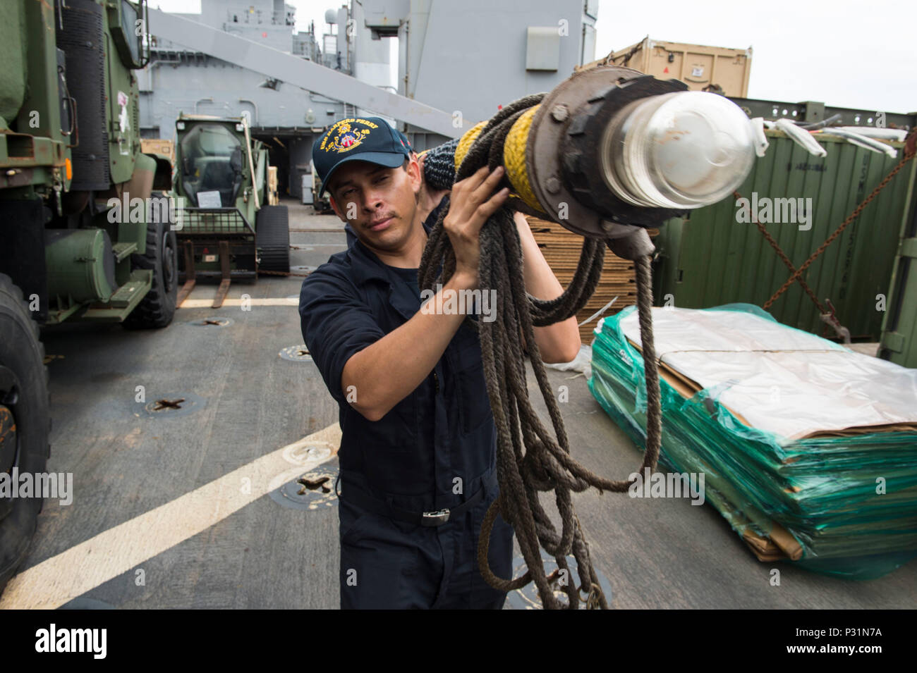 Seaman carries the flagstaff aboard dock landing ship USS Harpers Ferry ...