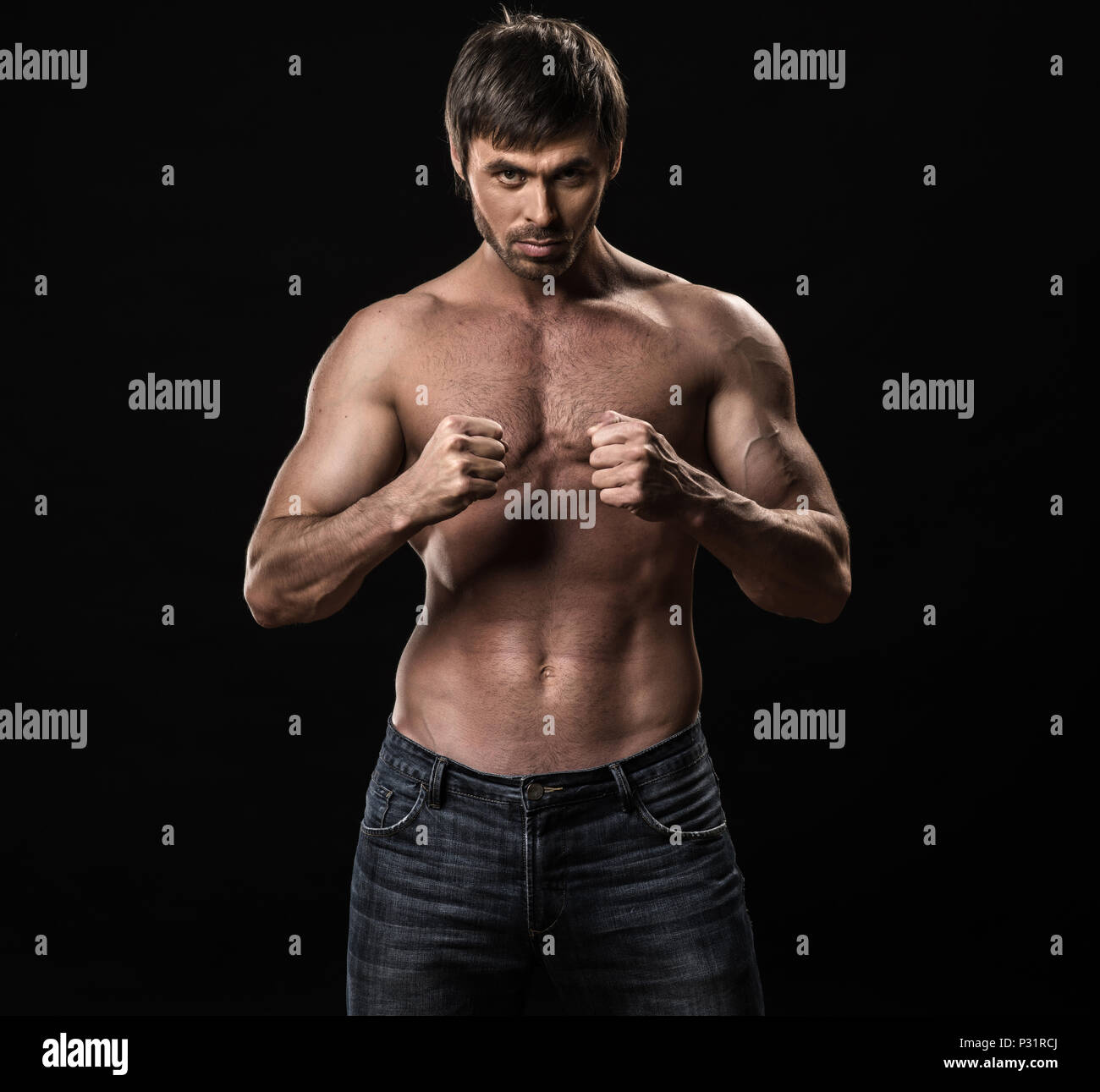 Muscular man on a black background, clasps hands in a fist Stock Photo ...