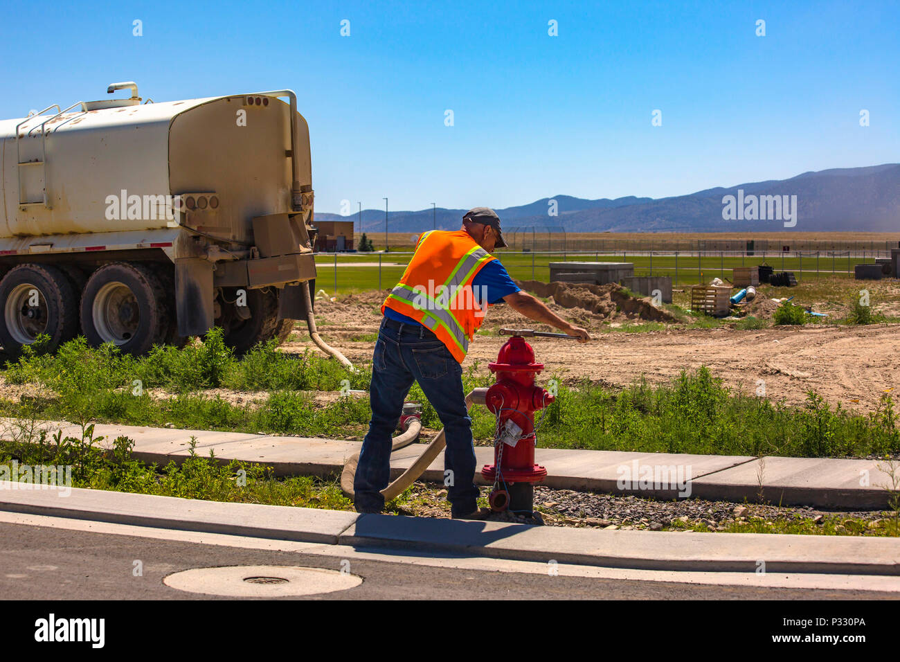 Man adjusting nozzle on fire hydrant with hose connected in ...