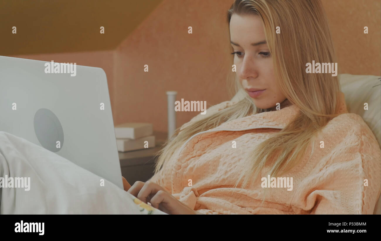 A sick patient lying in a hospital bed with a laptop Stock Photo - Alamy