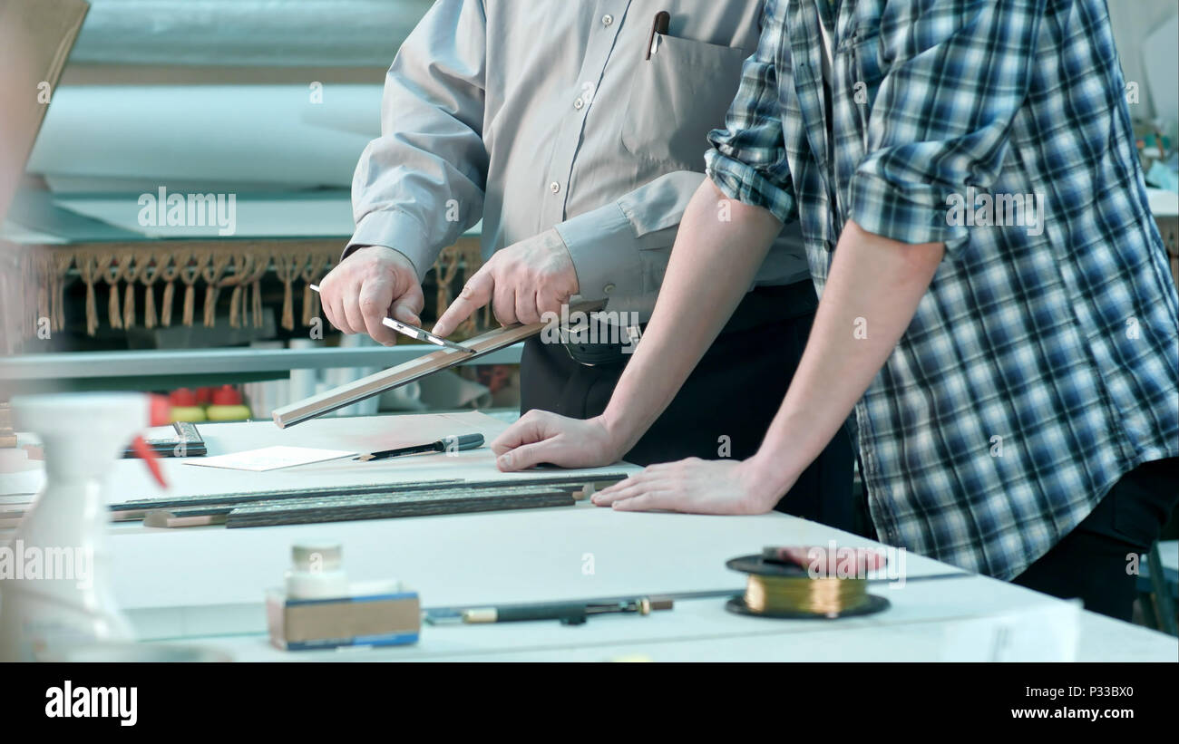 Male workers measuring size of frame behind the desk in workshop Stock ...