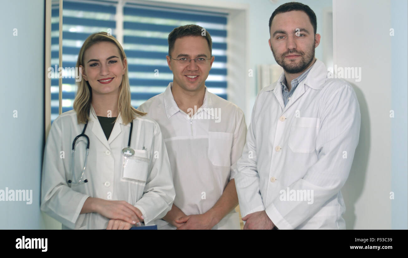 Two male doctors and female doctor with stethoscope smiling to the ...